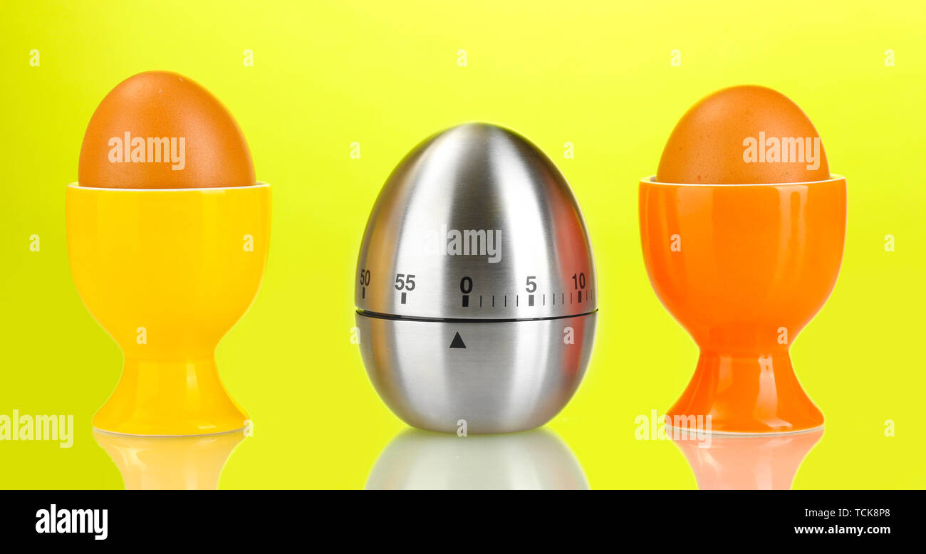 egg timer and egg in color stand on green background Stock Photo - Alamy