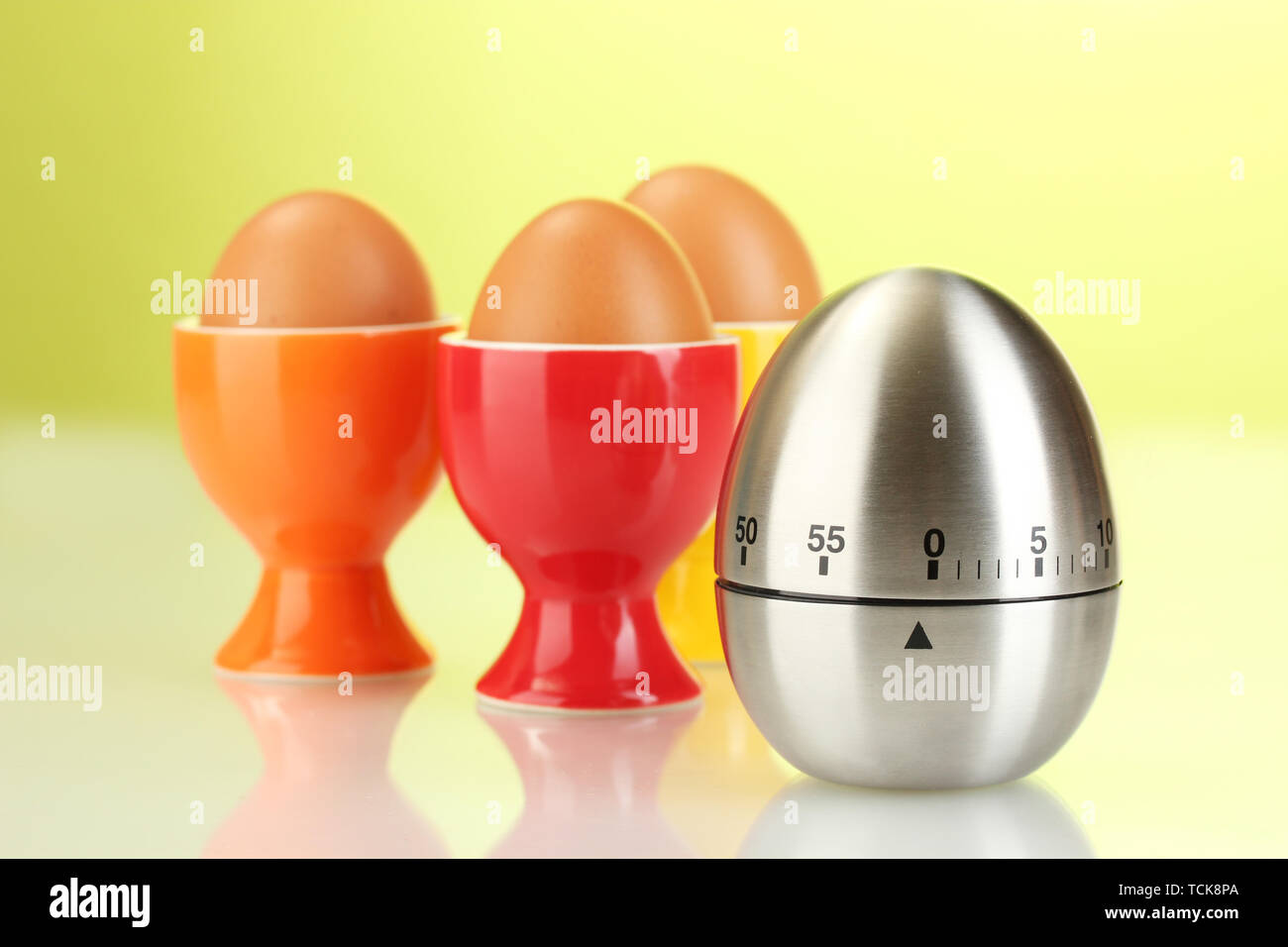 egg timer and egg in color stand on green background Stock Photo - Alamy