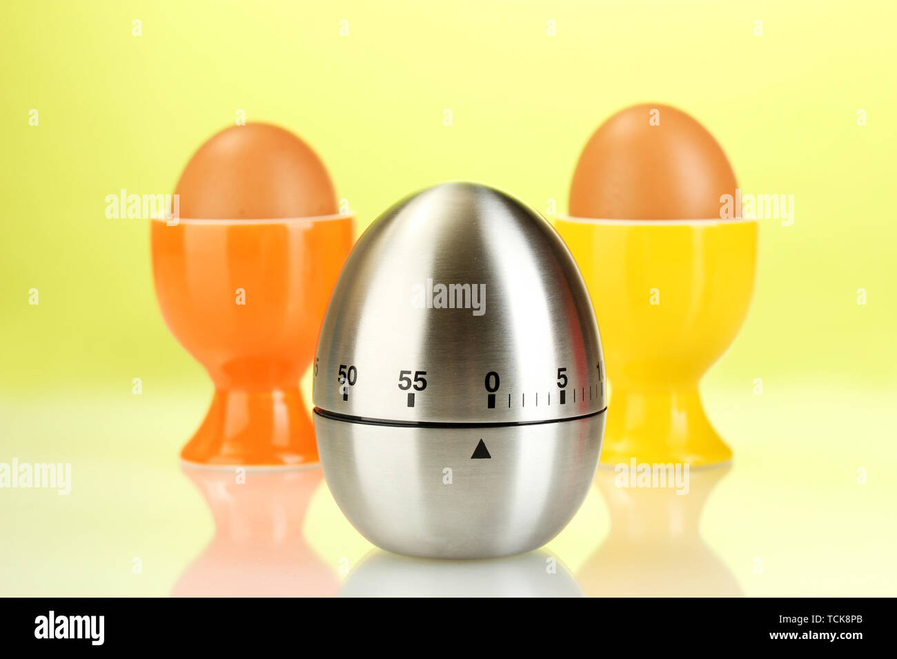 egg timer and egg in color stand on green background Stock Photo - Alamy