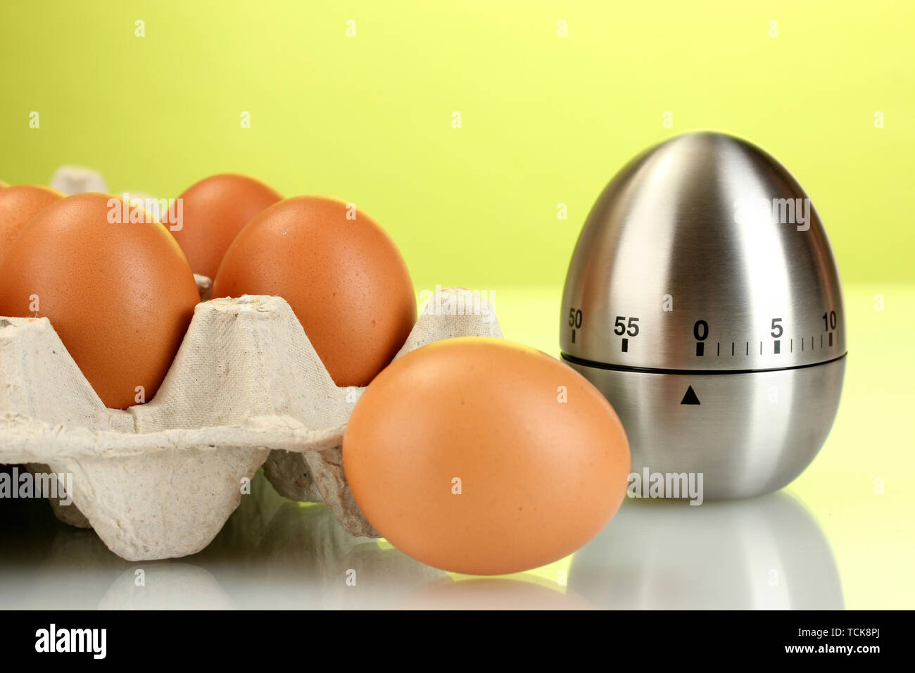 eggs in box and egg timer on green background Stock Photo - Alamy