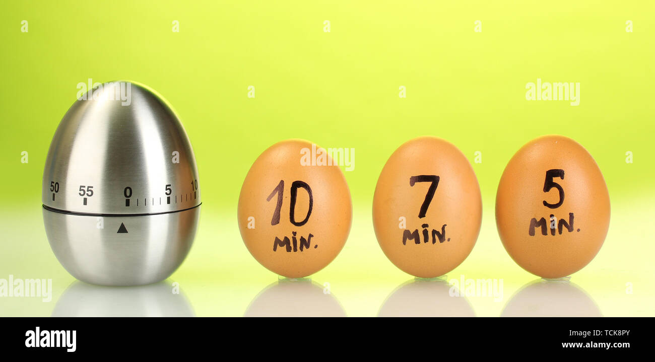 egg timer and eggs on green background Stock Photo - Alamy