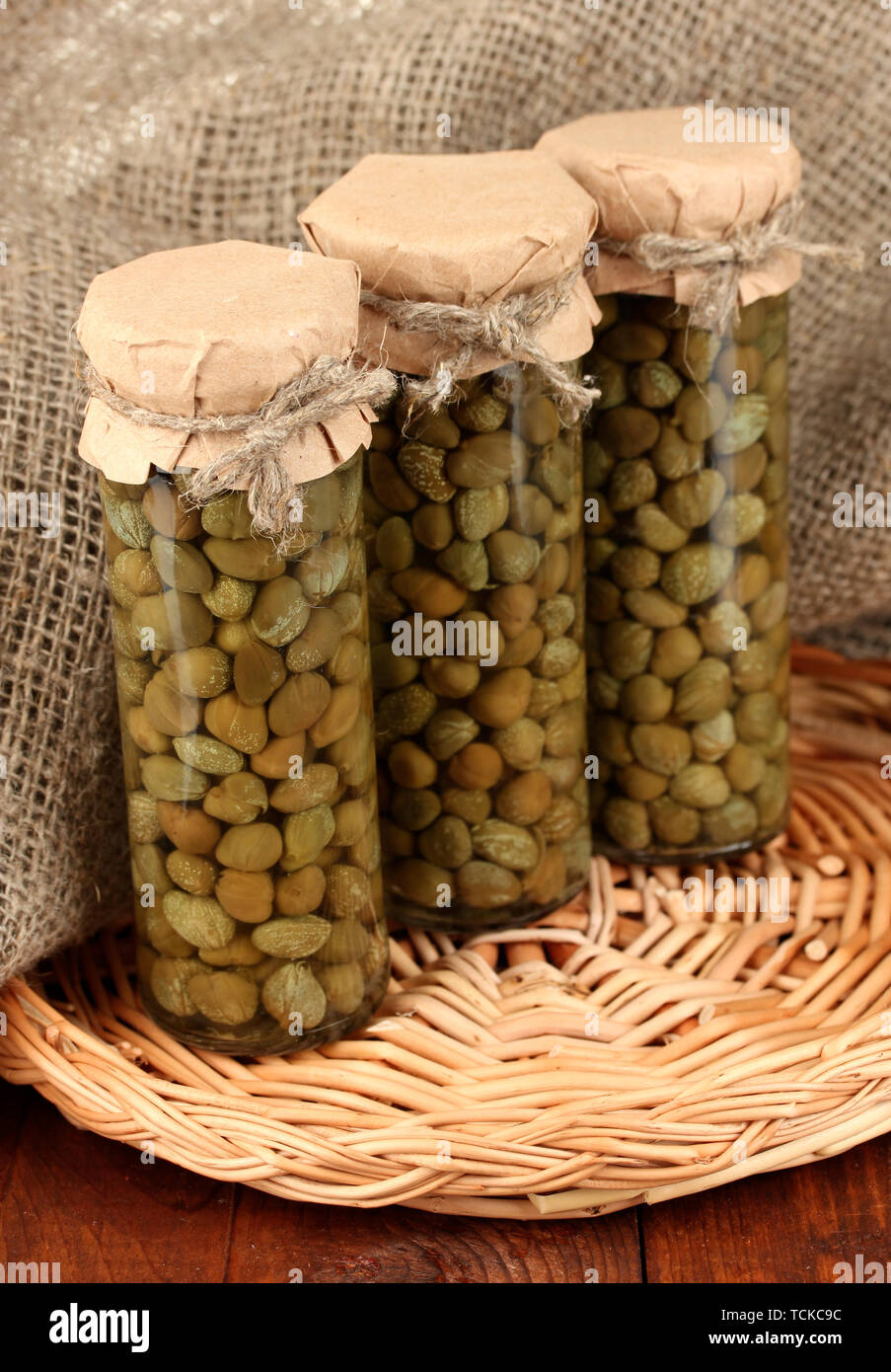 Glass jars with tinned capers on sack background close-up Stock Photo ...