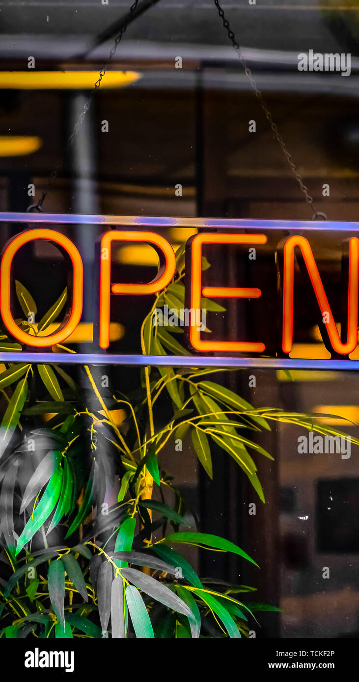 Panorama Close up of a neon open sign hanging on the glass wall of a ...