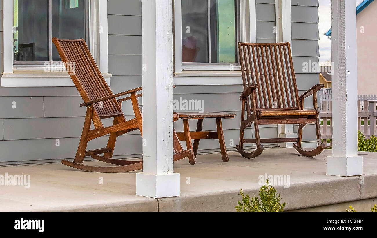 Panorama frame Front porch of a house with brown rocking chairs and ...