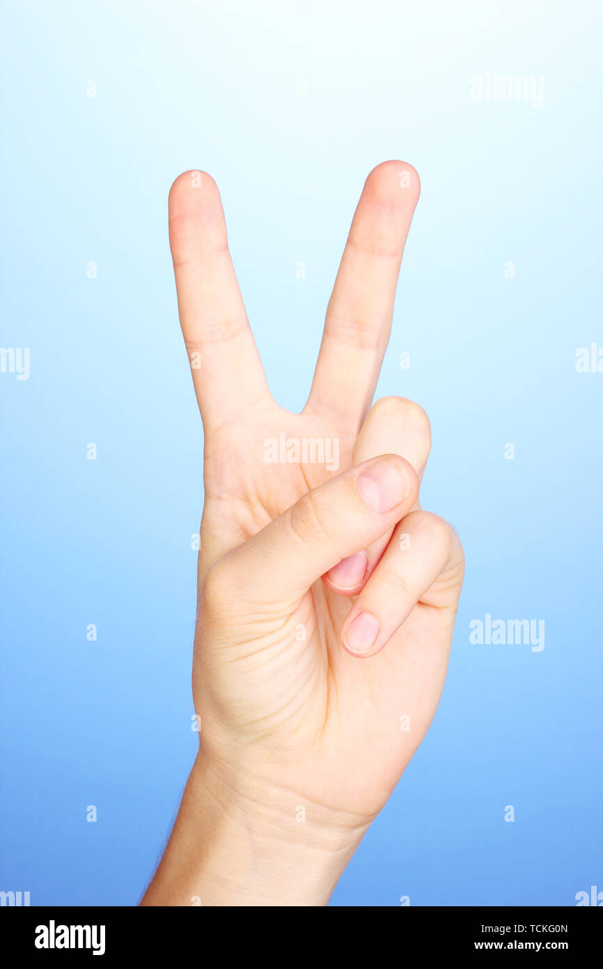 Hand making sign on blue background Stock Photo - Alamy