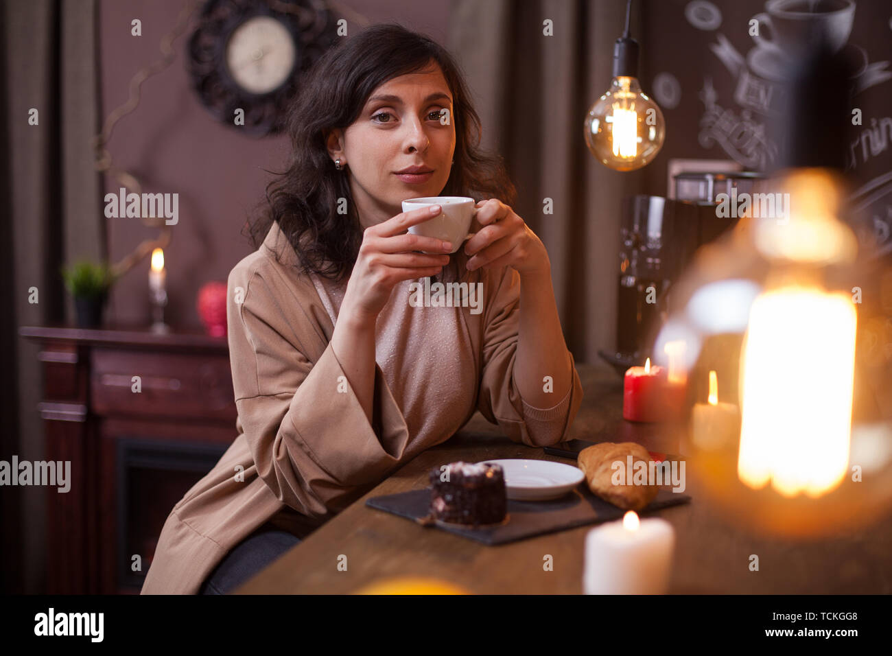Attractive girl drinking delicious coffee and looking at the camera in ...