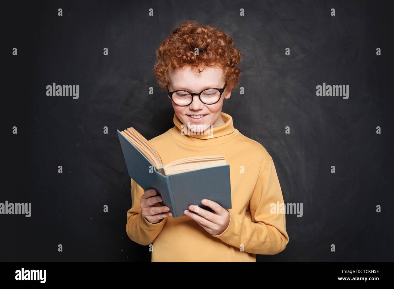 Kid reading a book on chalkboard background. Cute child boy, back to ...