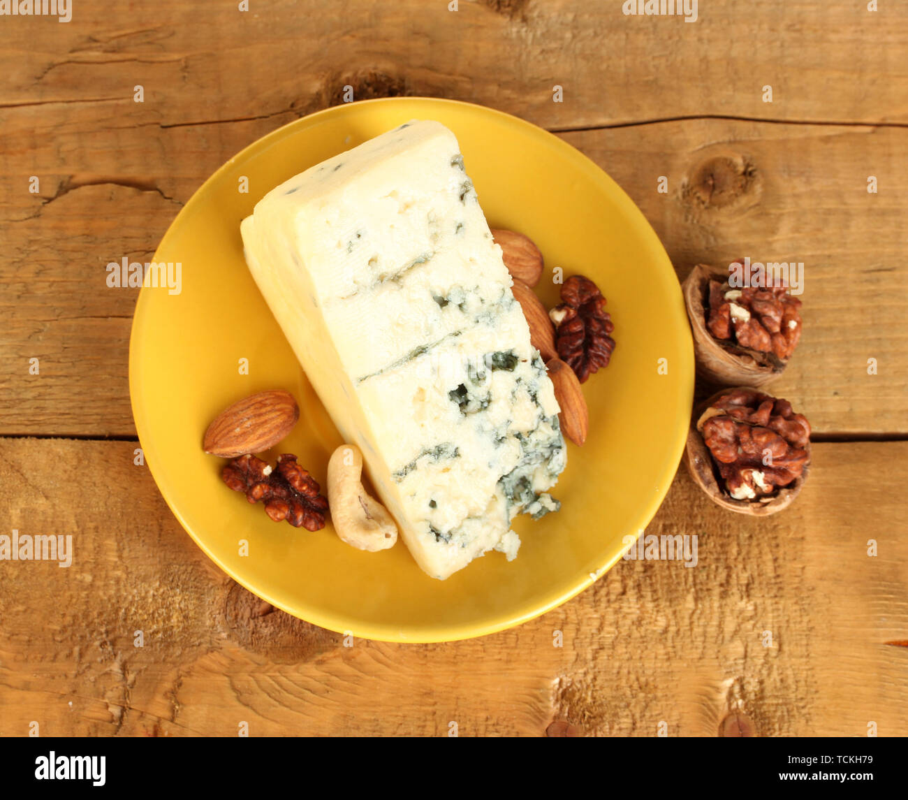 Cheese with mold and walnuts on the plate on wooden background close-up ...