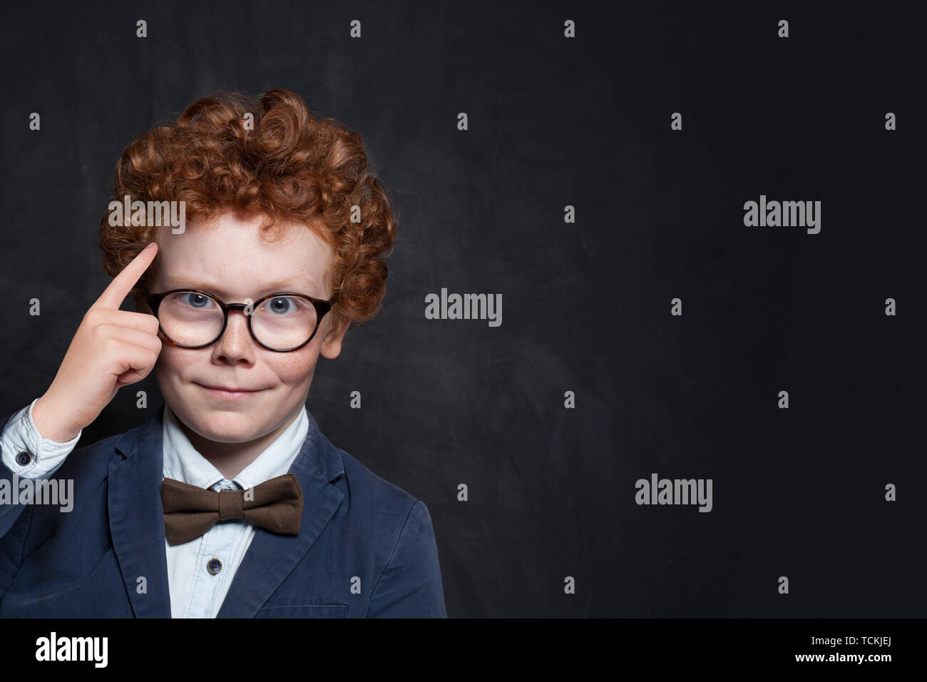 Smart child thinking on blackboard background. Brainstorming and idea ...