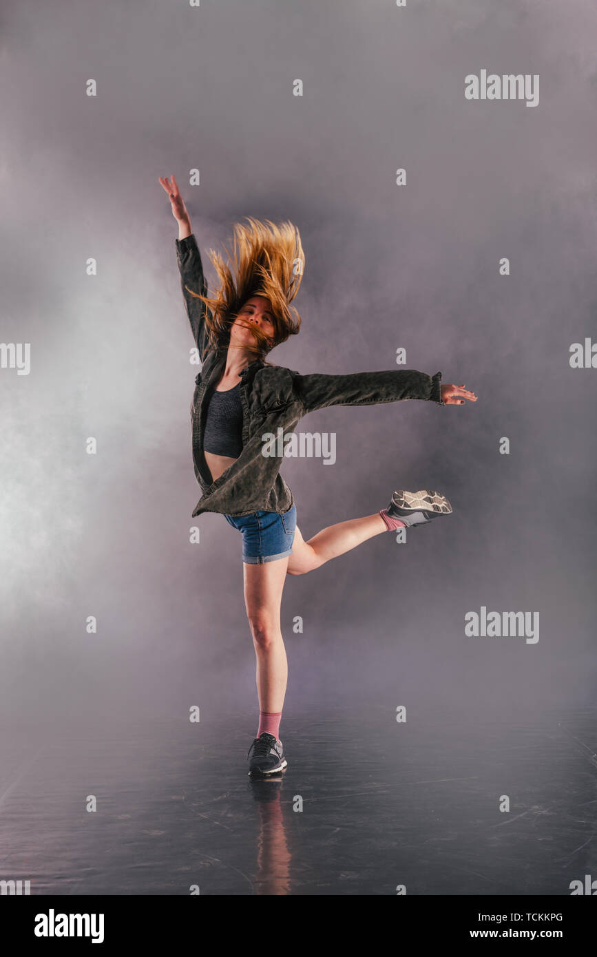 Female dancer shows off her elegance by moving her back leg high over ...