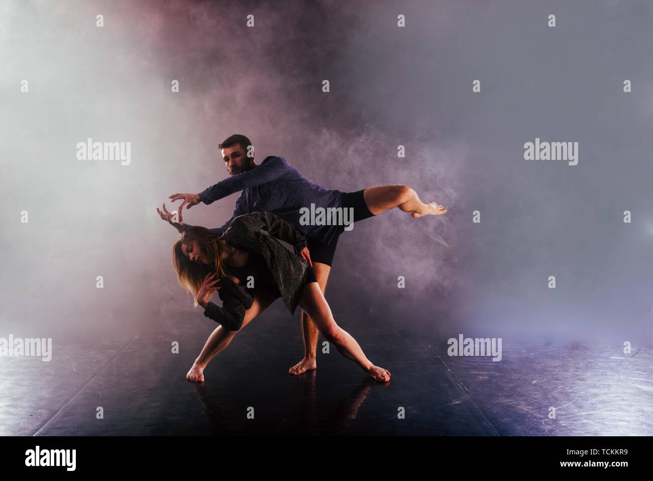 Two modern dancers stretching their shoeless feet high in the air ...