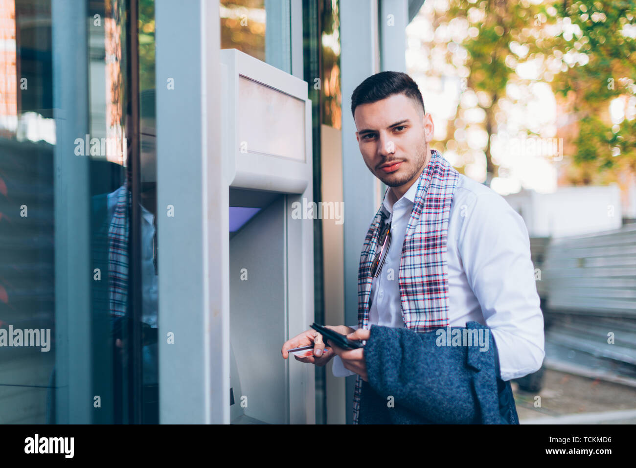 Stylish businessman in white shirt is holding his wallet and standing ...