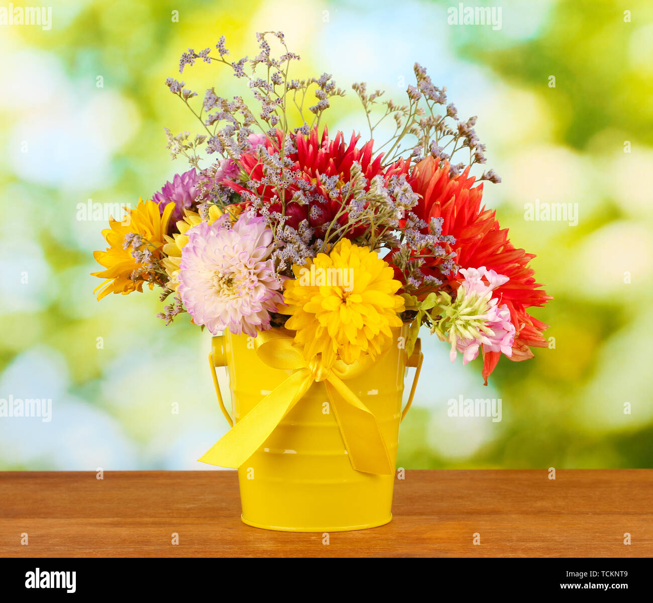 Bright yellow bucket with flowers on green background Stock Photo - Alamy