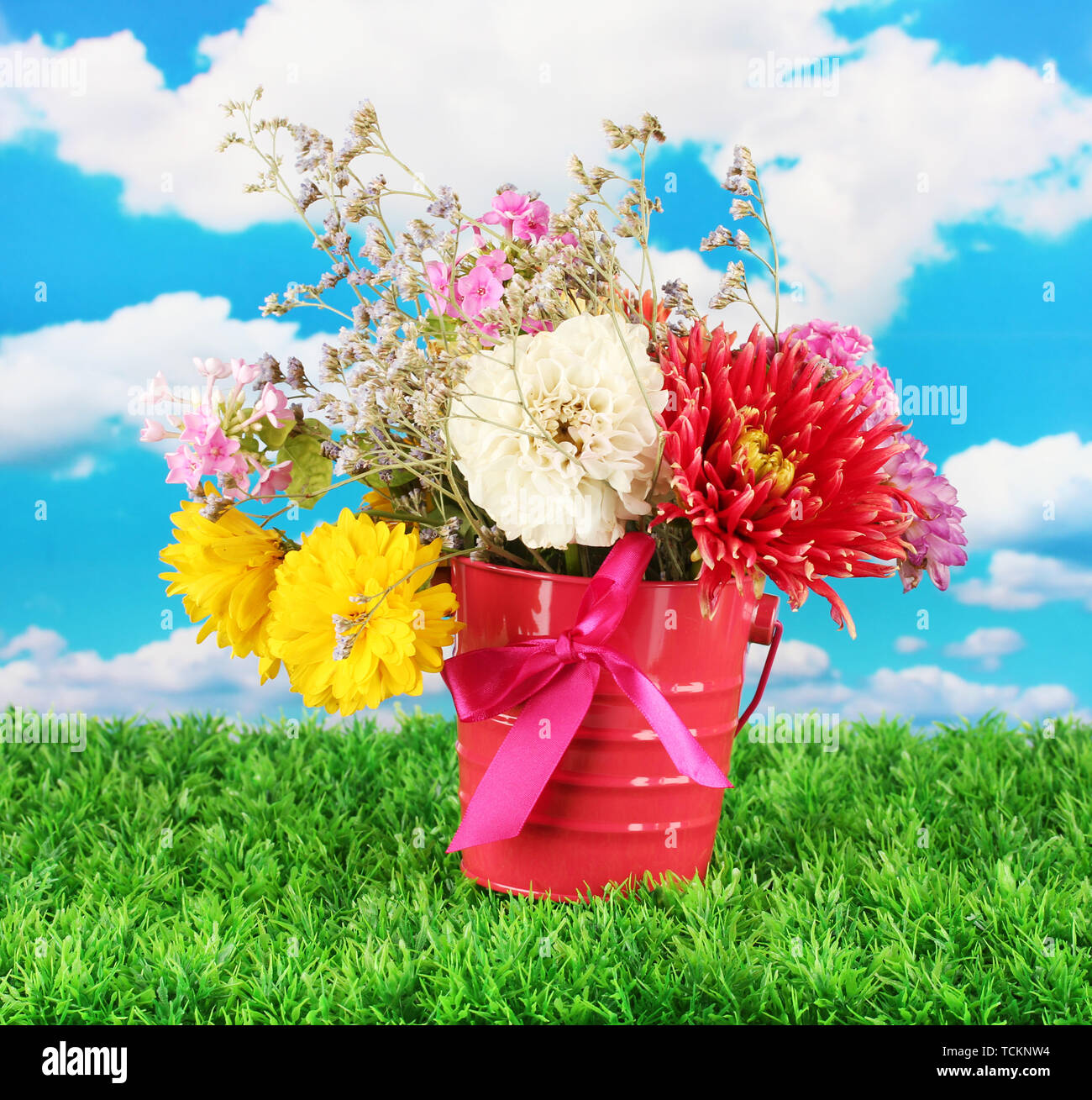 Bright pink bucket with flowers on sky background Stock Photo - Alamy