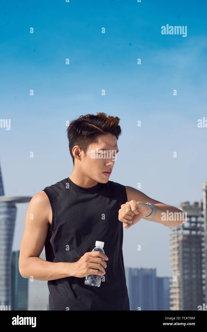 Young male athlete checking smartwatch, over shoulder view Stock Photo ...