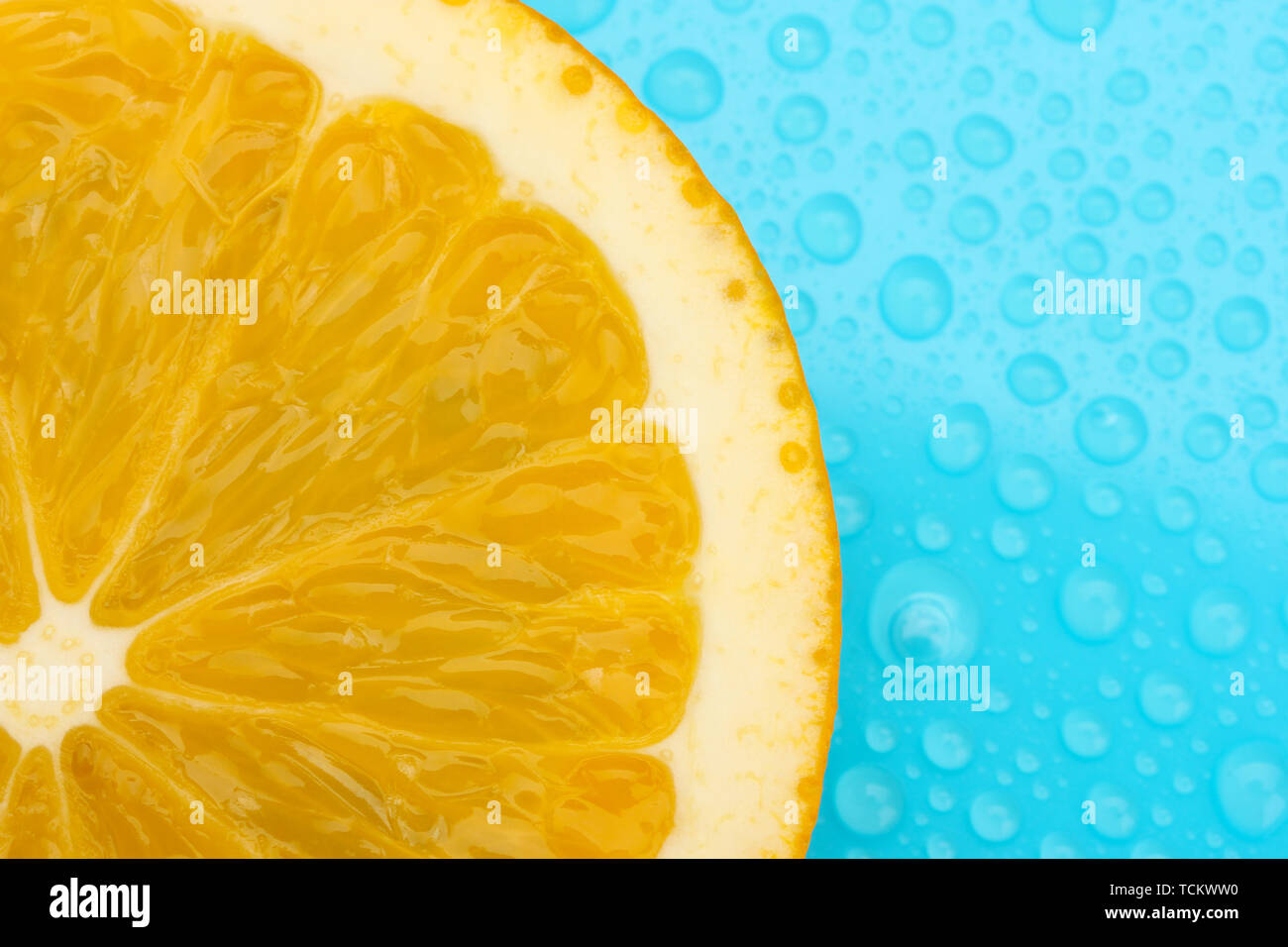 Slice of lime with drop on blue background Stock Photo - Alamy