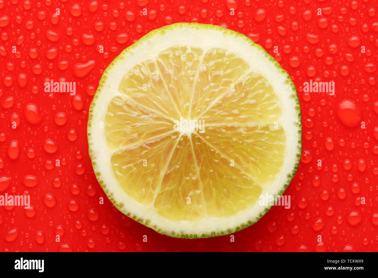 Slice of lemon with drop on red background Stock Photo - Alamy