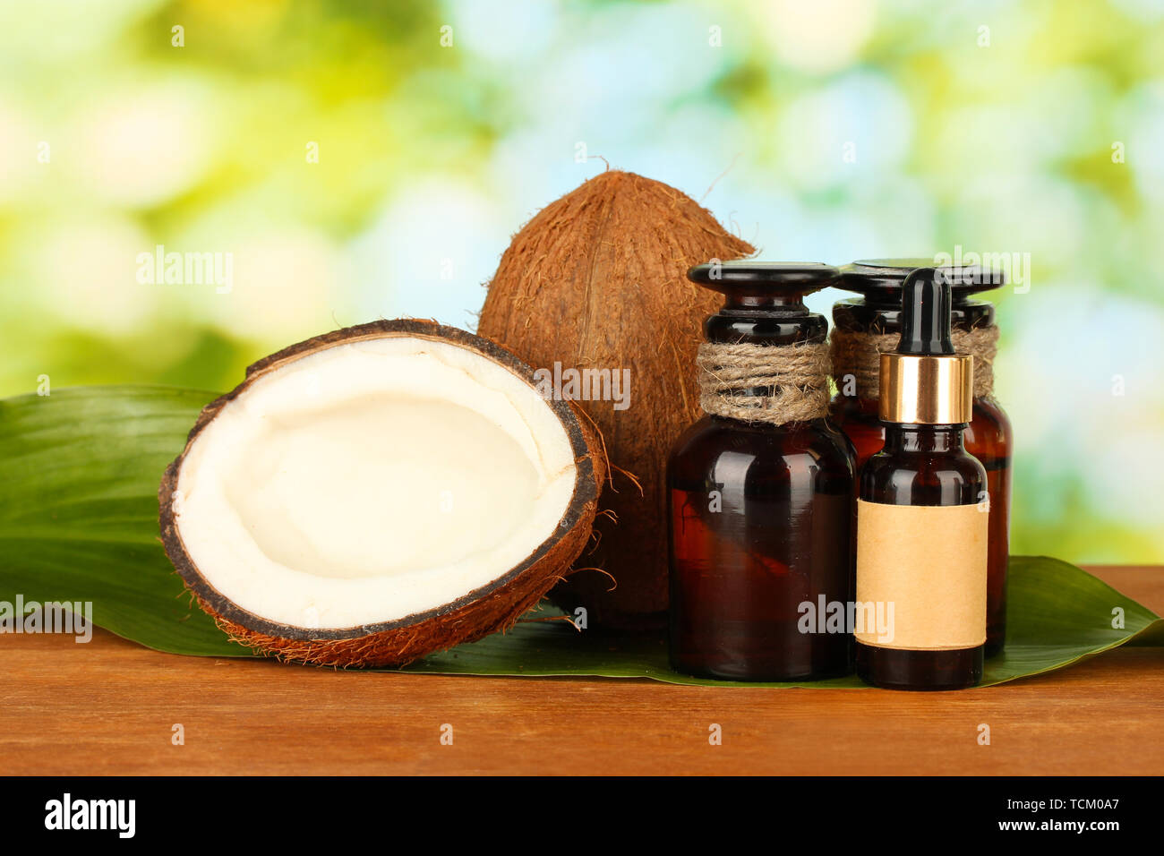 coconut oil in bottles with coconuts on green background Stock Photo ...