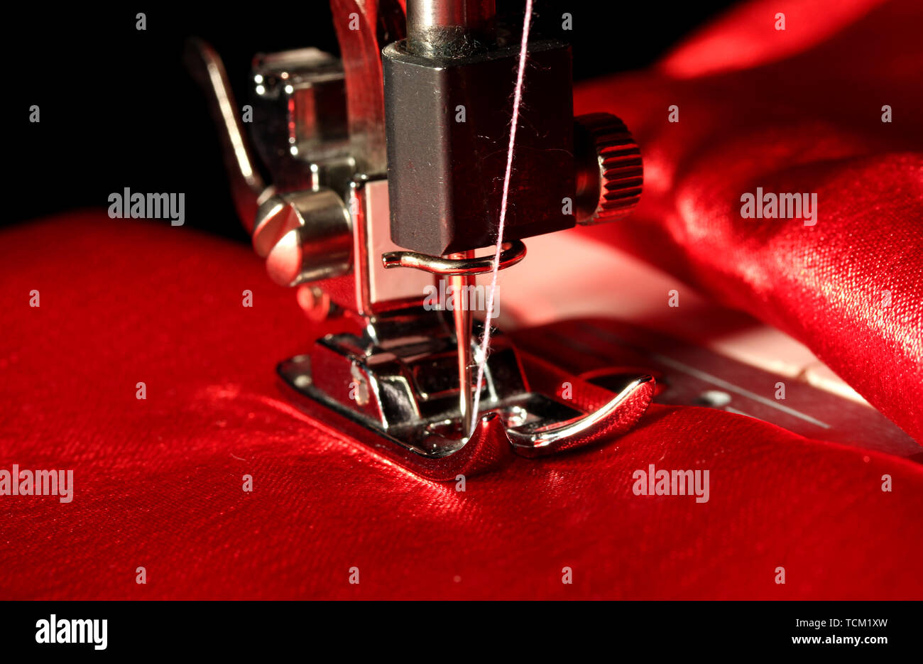 Sewing machine with red cloth closeup Stock Photo - Alamy