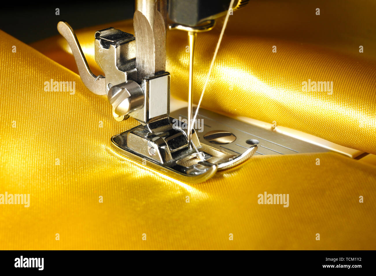 Sewing machine with gold cloth closeup Stock Photo - Alamy