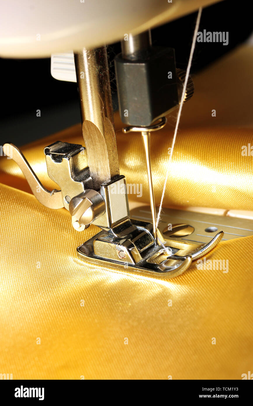 Sewing machine with gold cloth closeup Stock Photo - Alamy