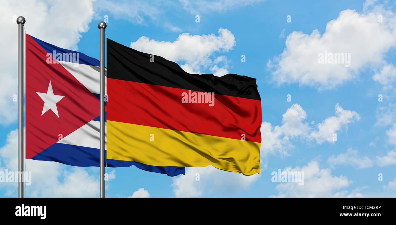 Cuba and Germany flag waving in the wind against white cloudy blue sky ...