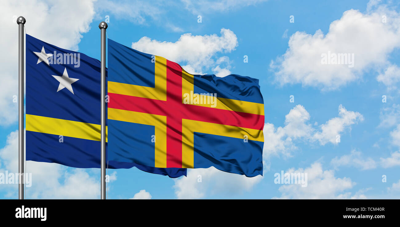 Curacao and Aland Islands flag waving in the wind against white cloudy ...