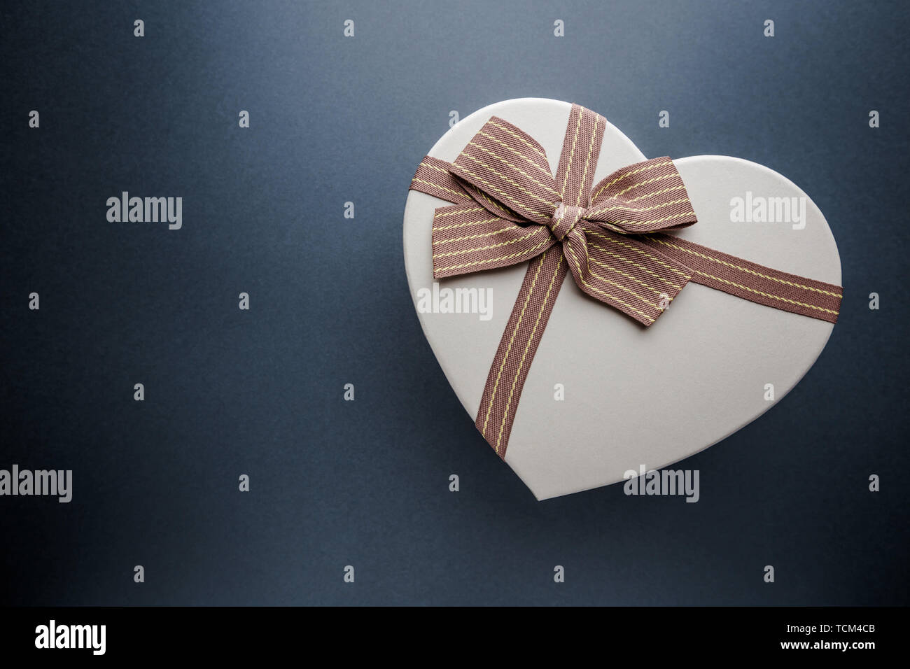 Heart shaped cardboard gift box with bow on black background Stock Photo - Alamy