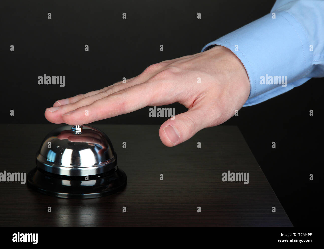 Hand ringing in service bell on wooden table on black background Stock ...