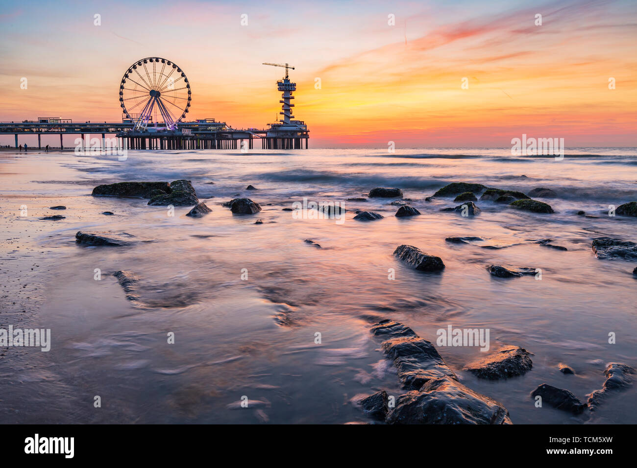 Colorful sunset on coastline, beach, pier and ferris wheel ...