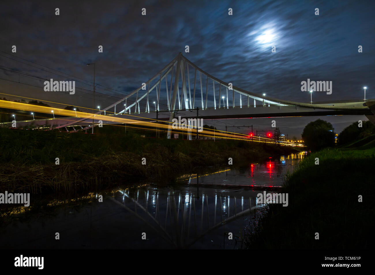 Suspension bridge at night under moonlight with light trails of moving ...