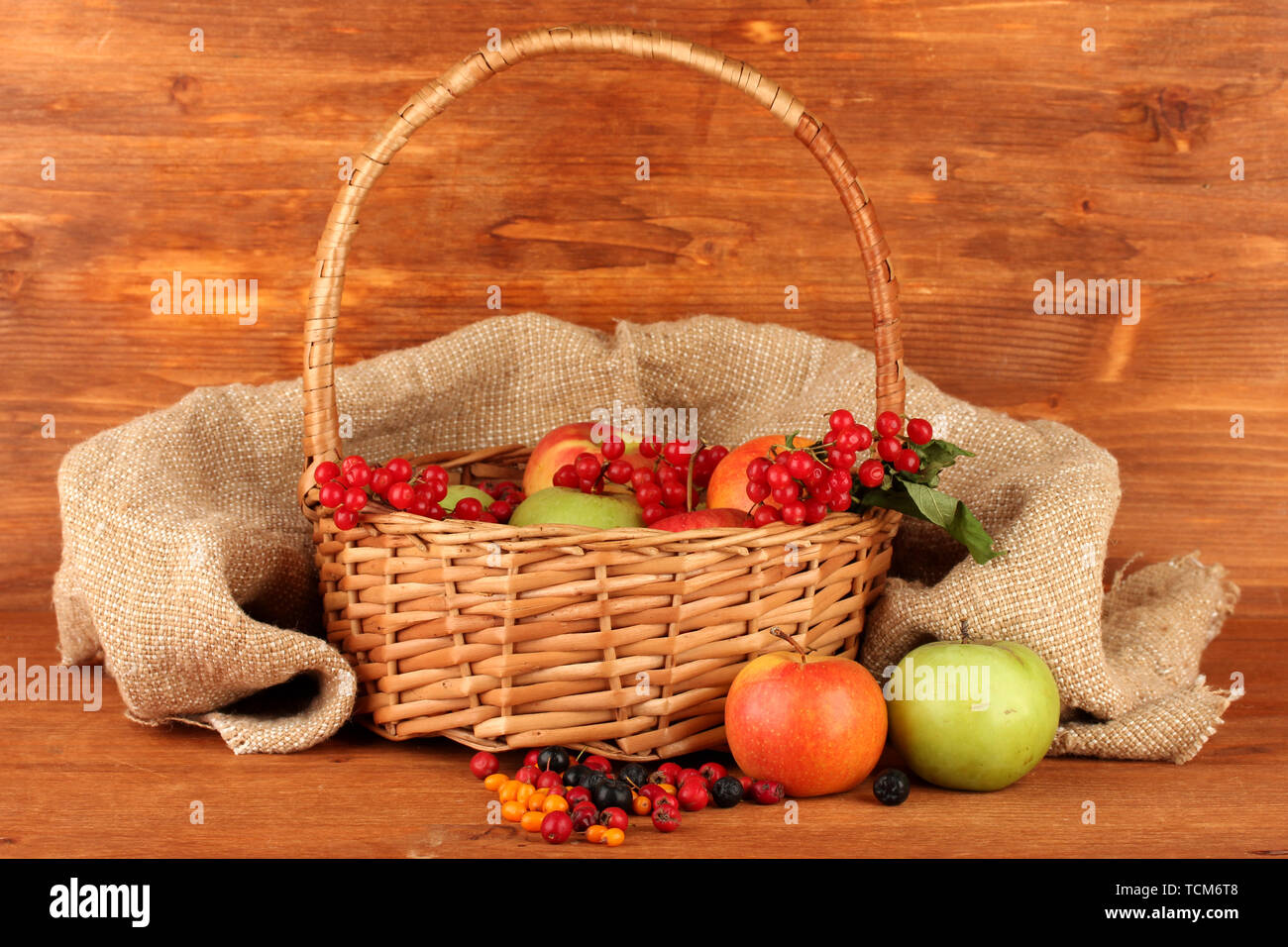 crop of berries and fruits in a basket on wooden background close-up ...