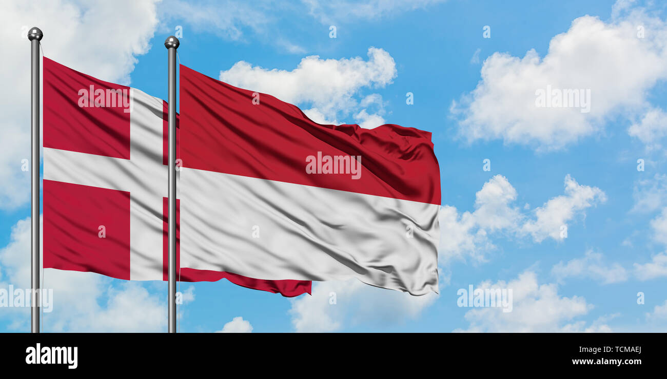 Denmark and Indonesia flag waving in the wind against white cloudy blue ...
