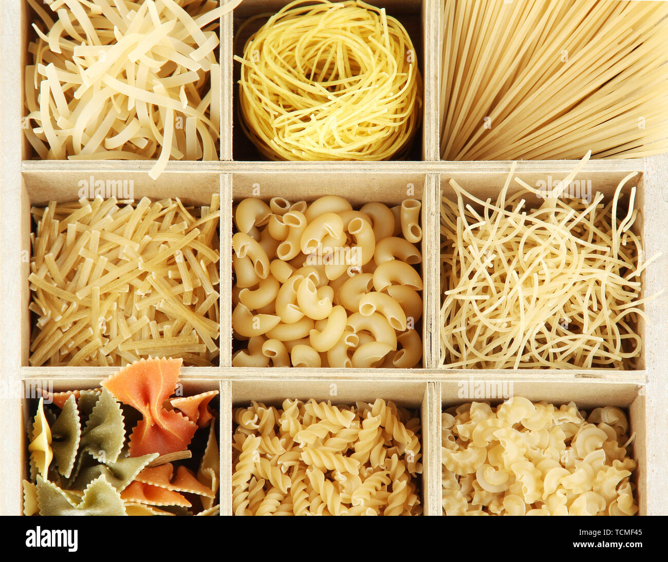Nine types of pasta in wooden box sections close-up isolated on white ...