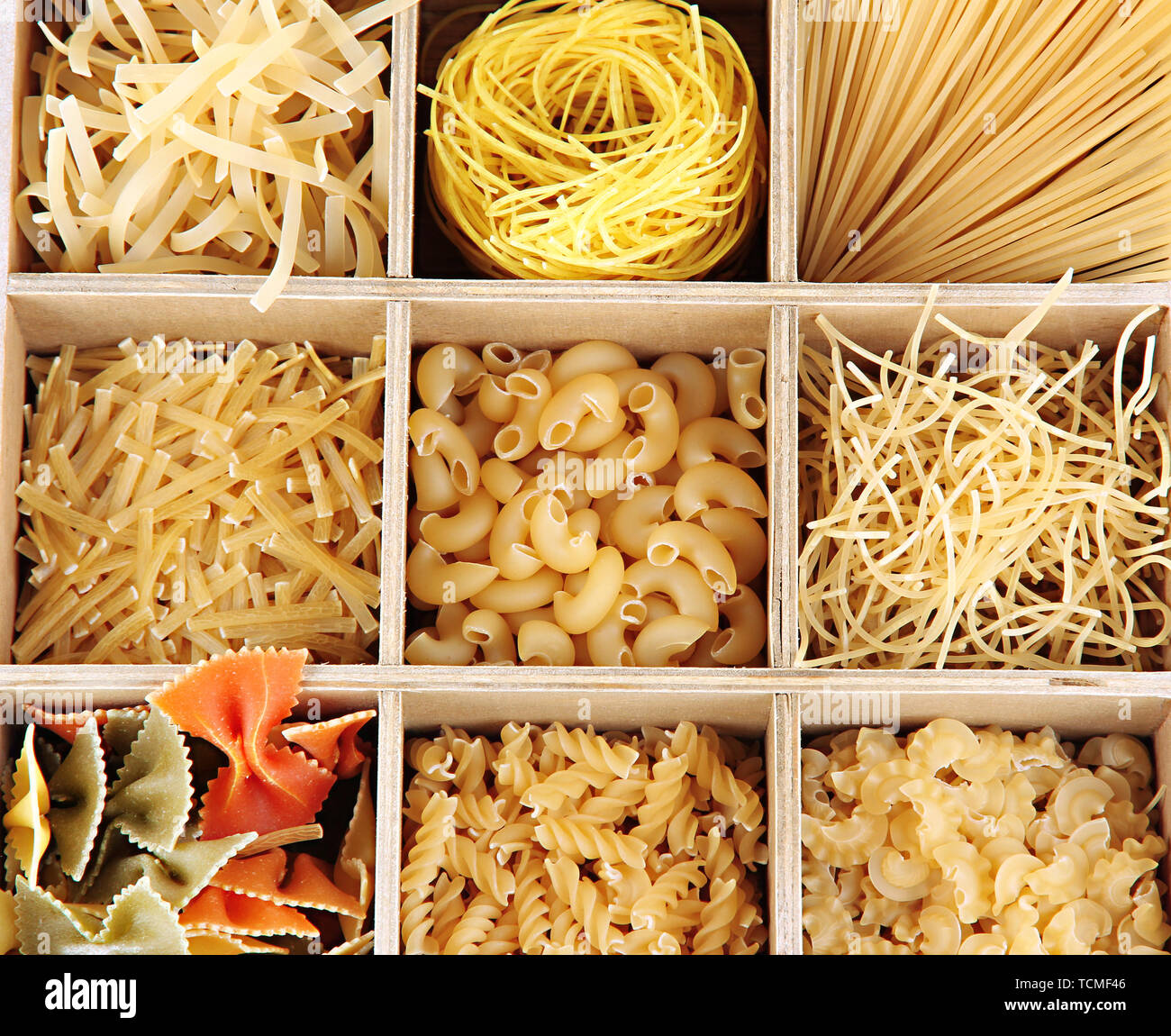 Nine types of pasta in wooden box sections close-up isolated on white ...