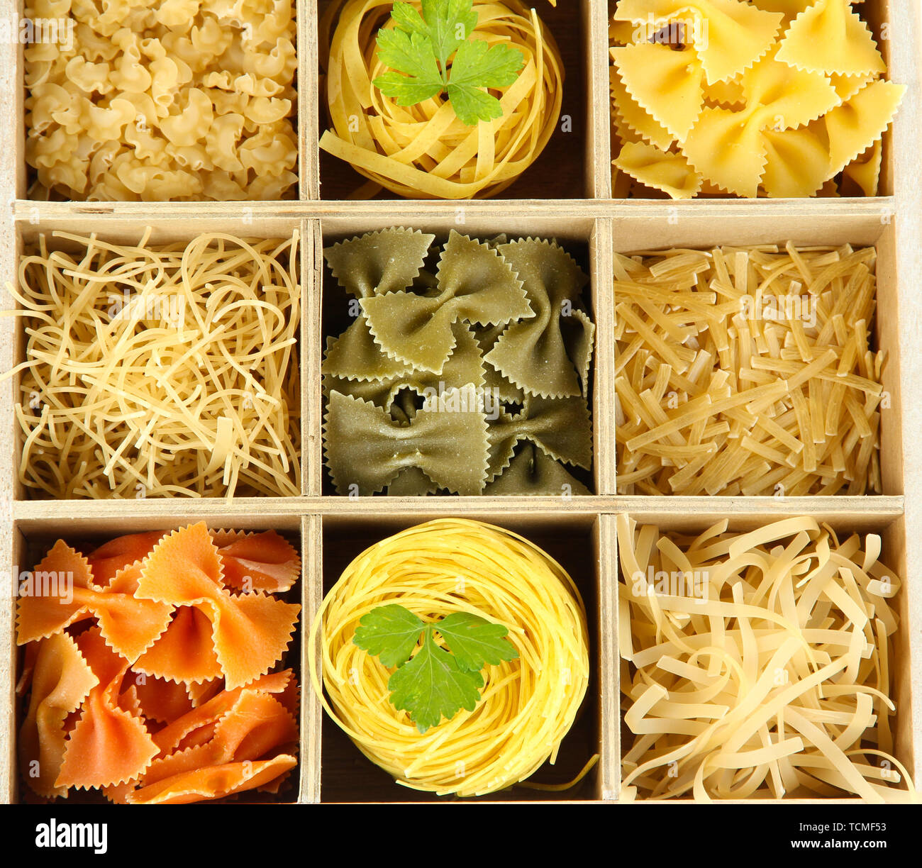 Nine types of pasta in wooden box sections close-up isolated on white ...