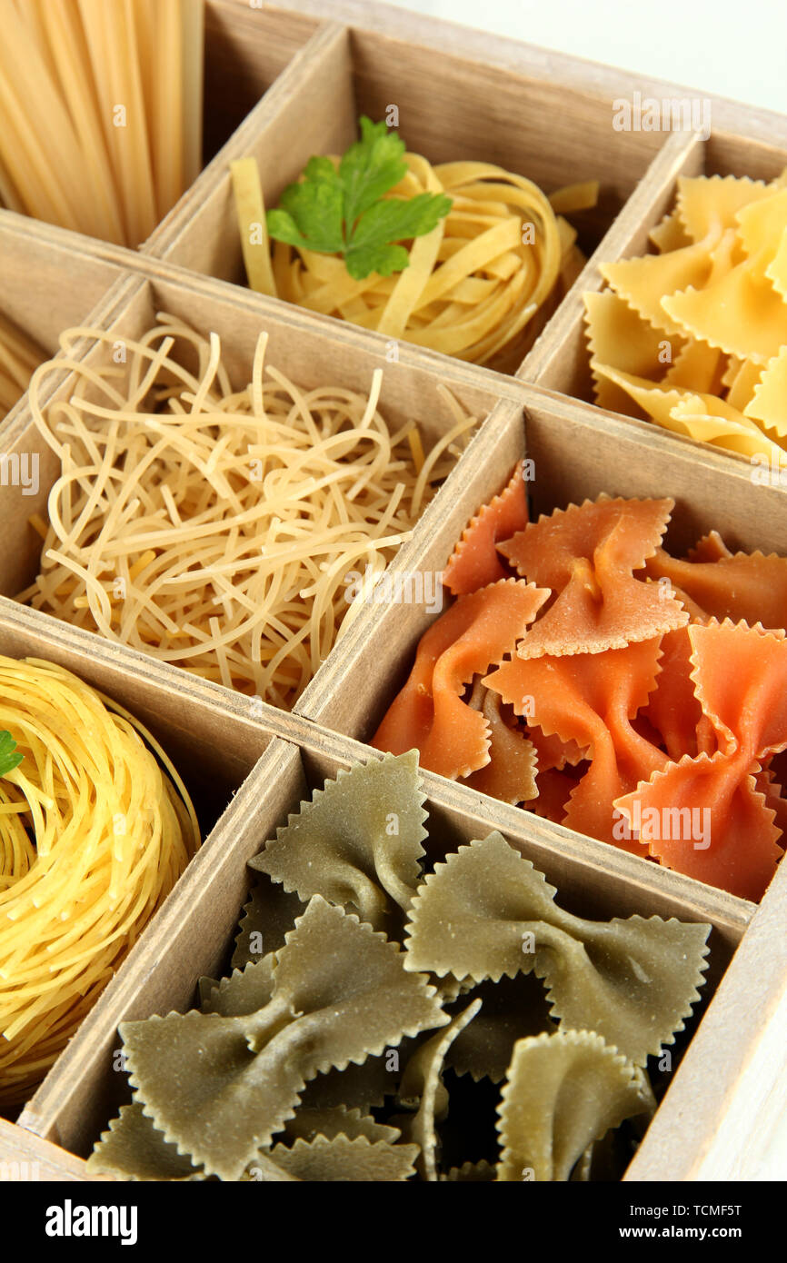 Nine types of pasta in wooden box sections close-up isolated on white ...