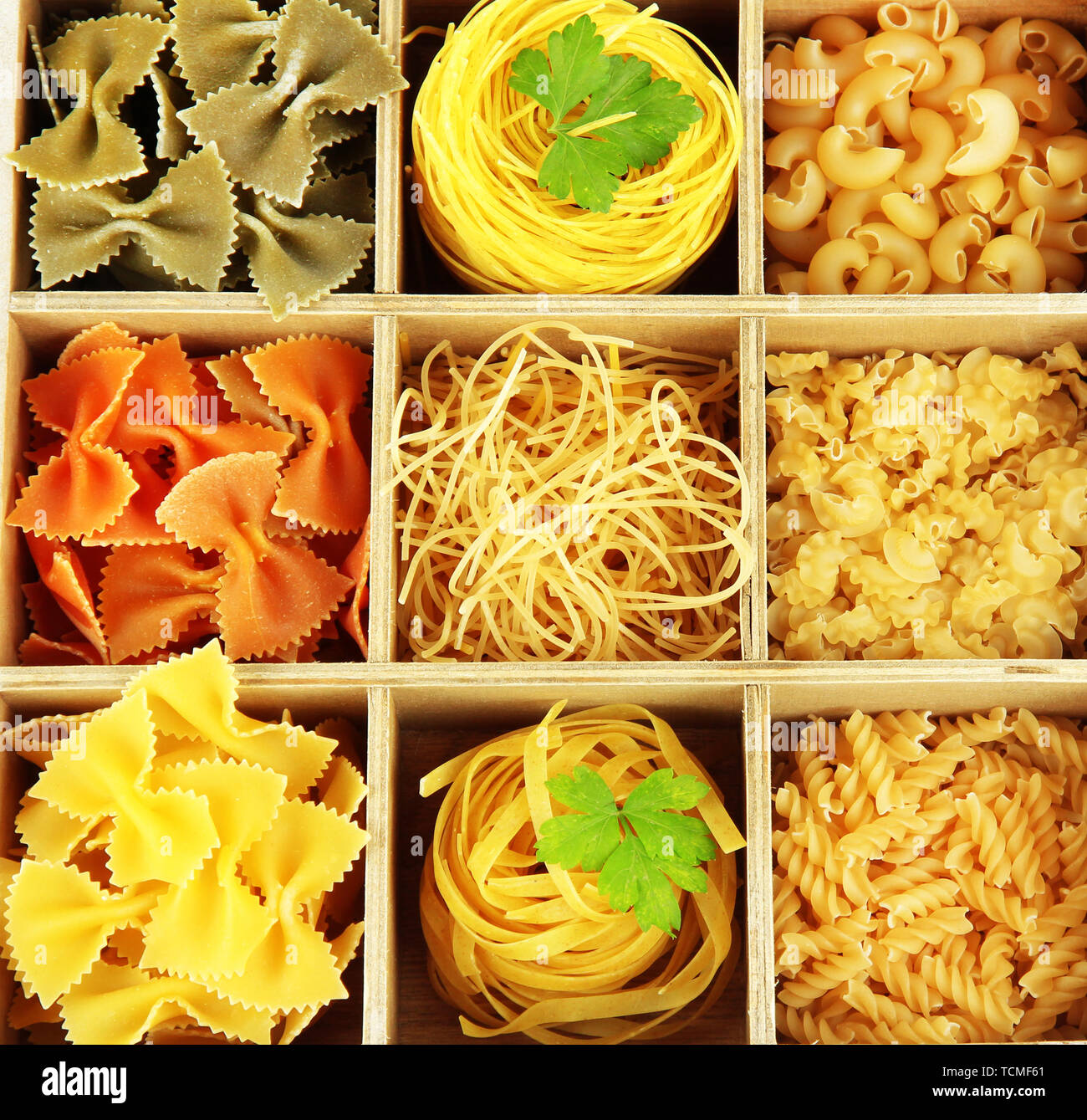 Nine types of pasta in wooden box sections close-up isolated on white ...