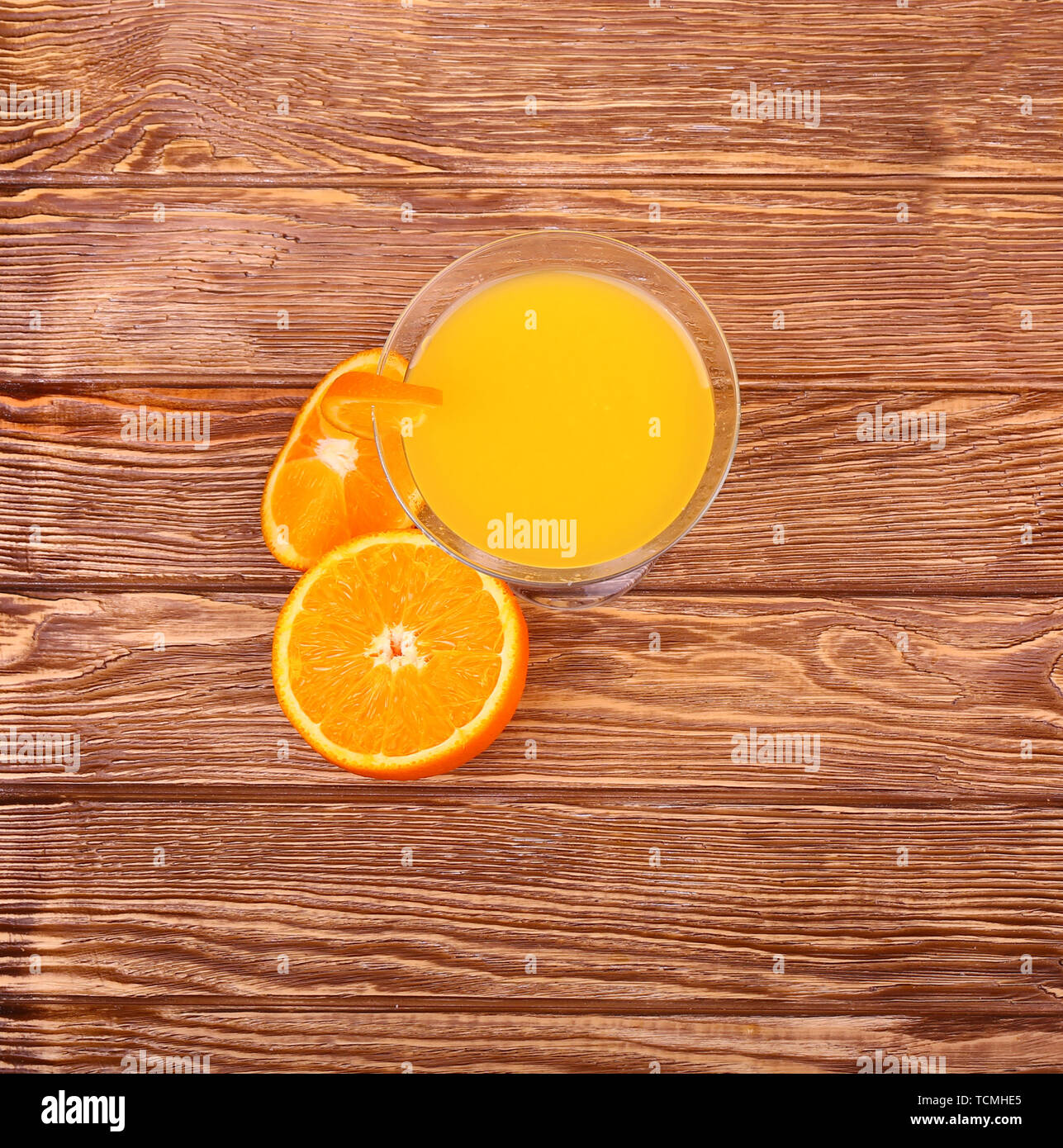 Glass of freshly pressed orange juice with sliced orange half on wooden ...
