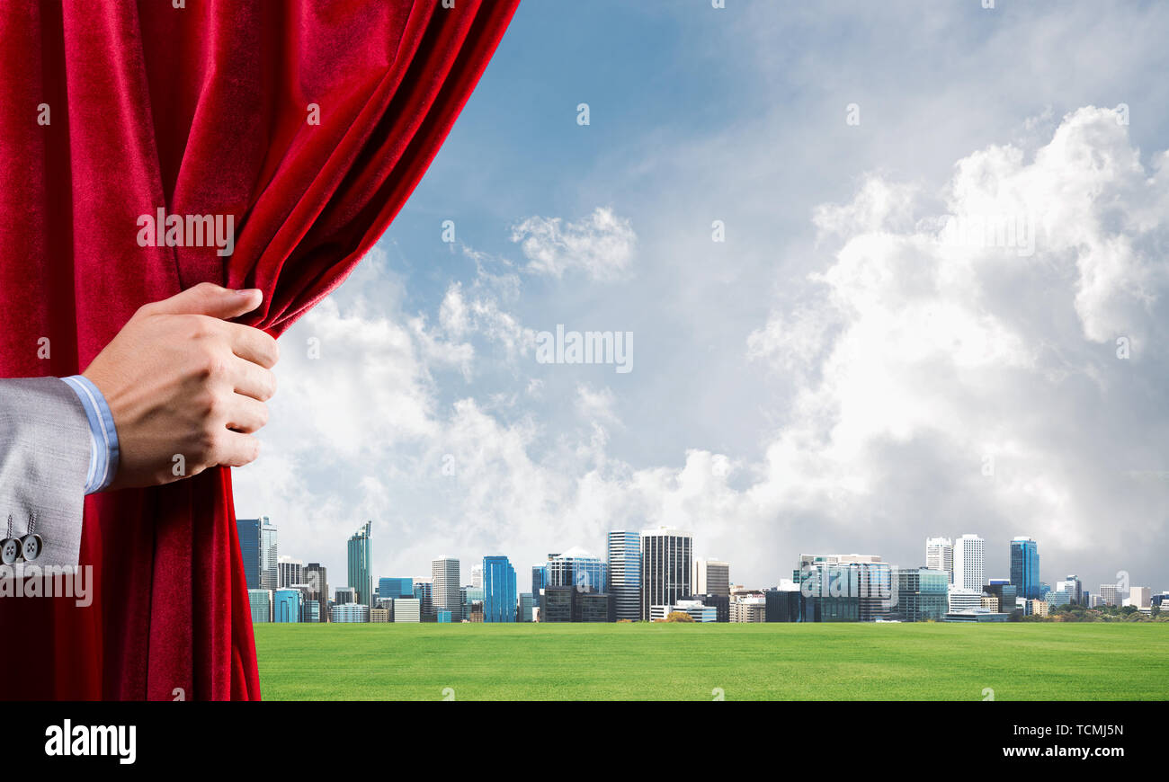 Green meadow behind red curtain and hand holding it Stock Photo - Alamy
