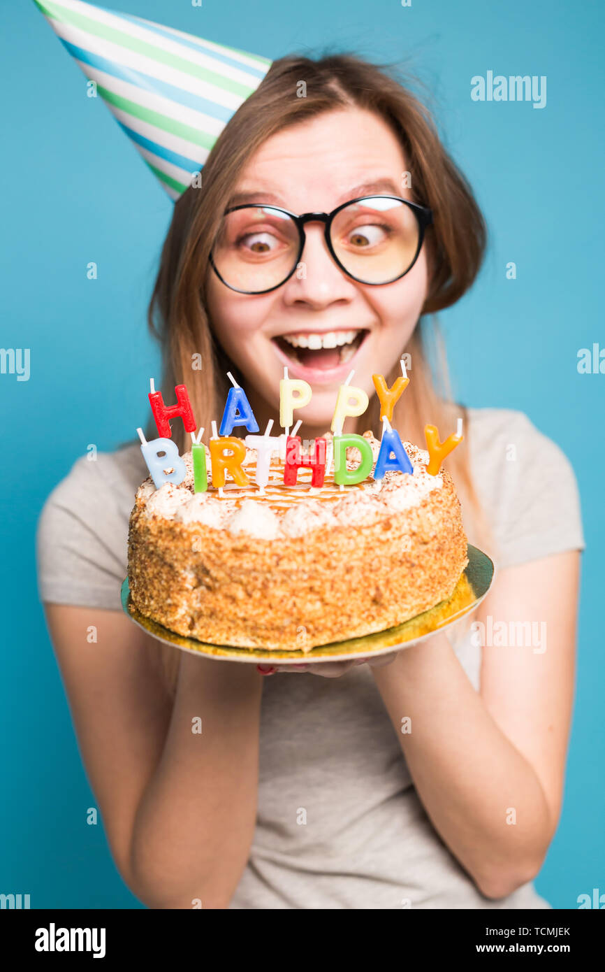 Crazy funny girl in a paper hat and glasses holding a big birthday cake ...
