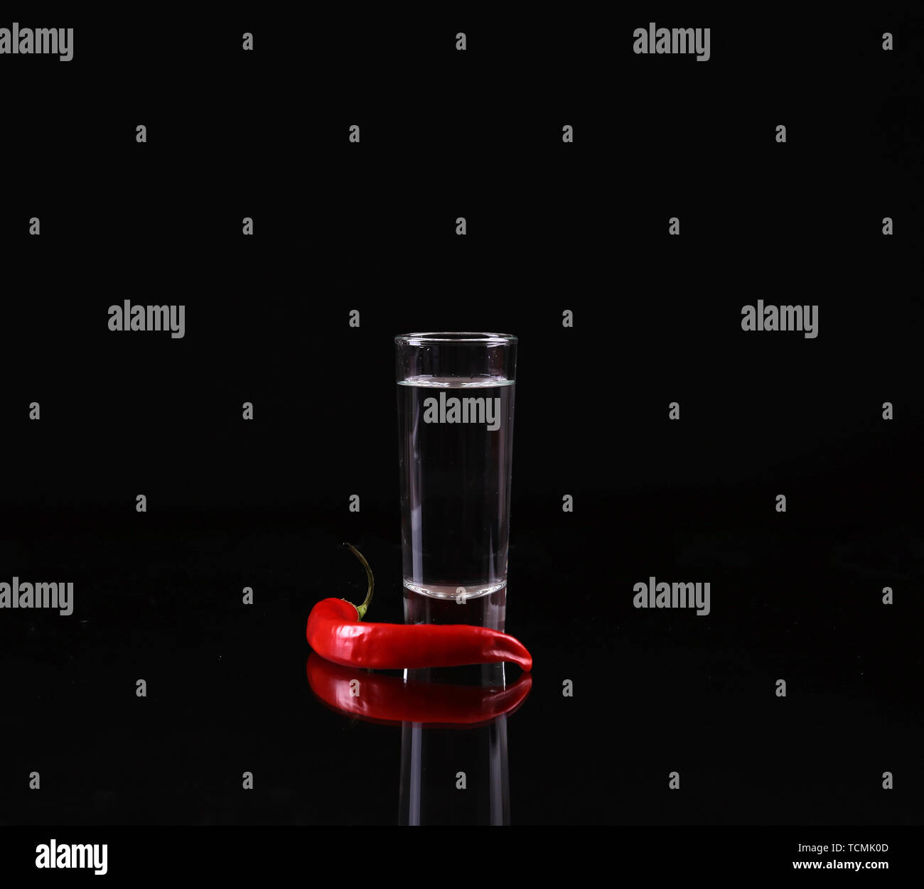 Shot of vodka with chili peppers on a black background Stock Photo - Alamy