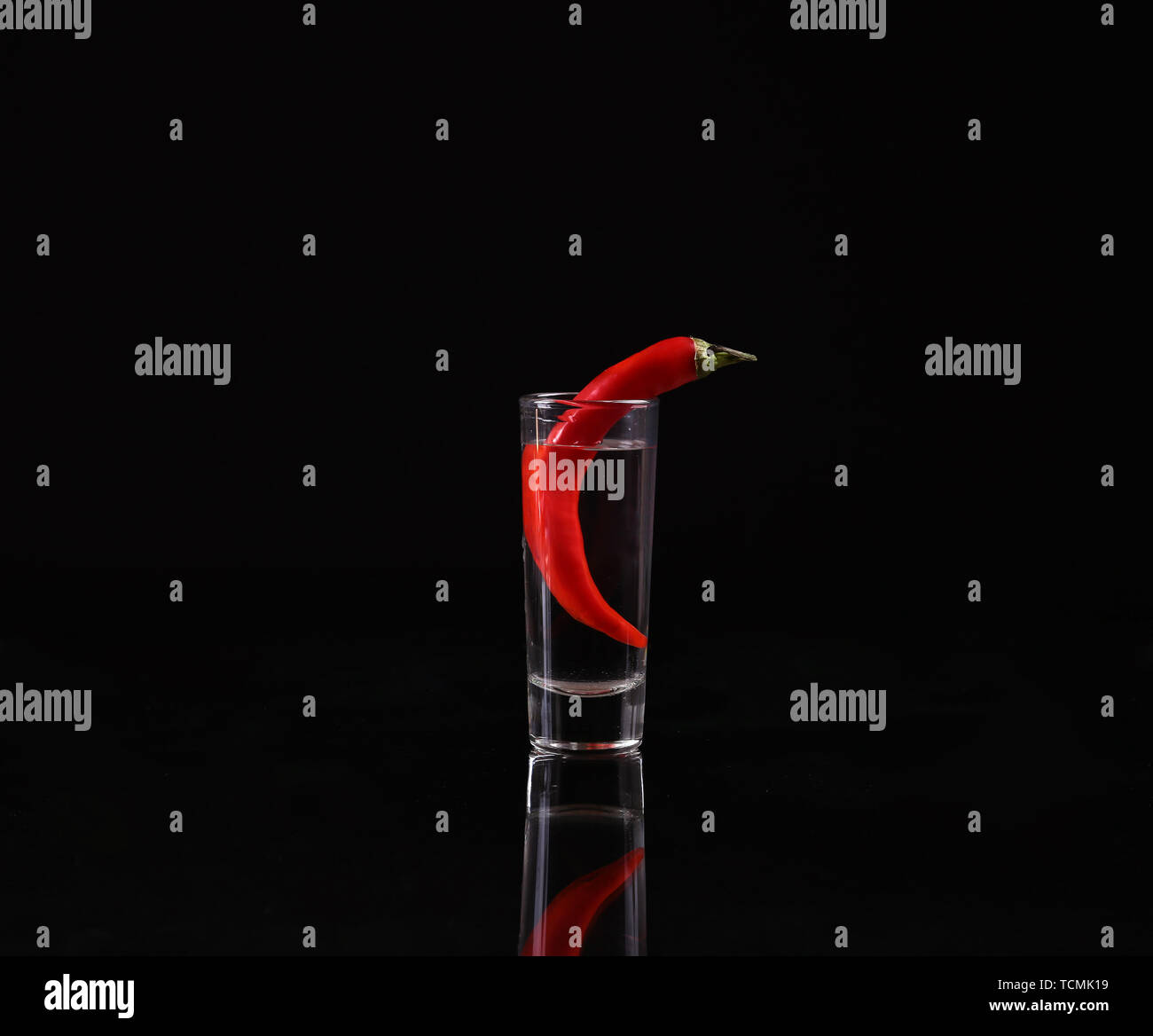 Shot of vodka with chili peppers on a black background Stock Photo - Alamy