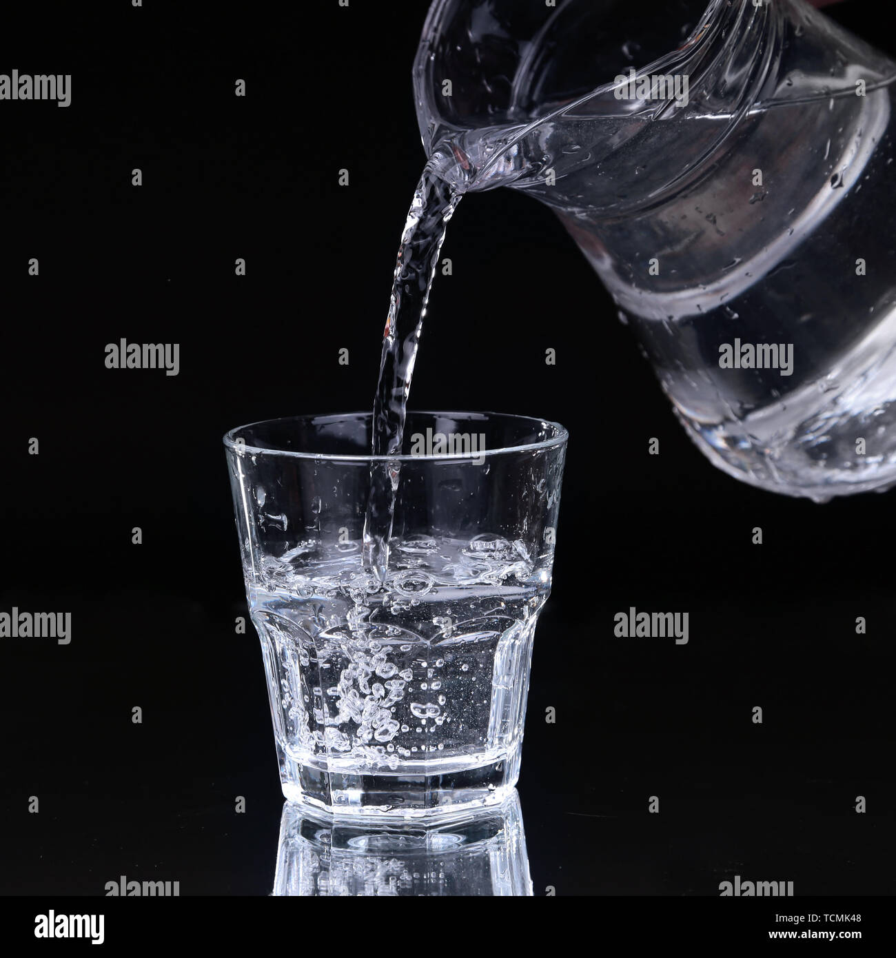 Water pitcher pouring a glass of fresh water on black background Stock ...