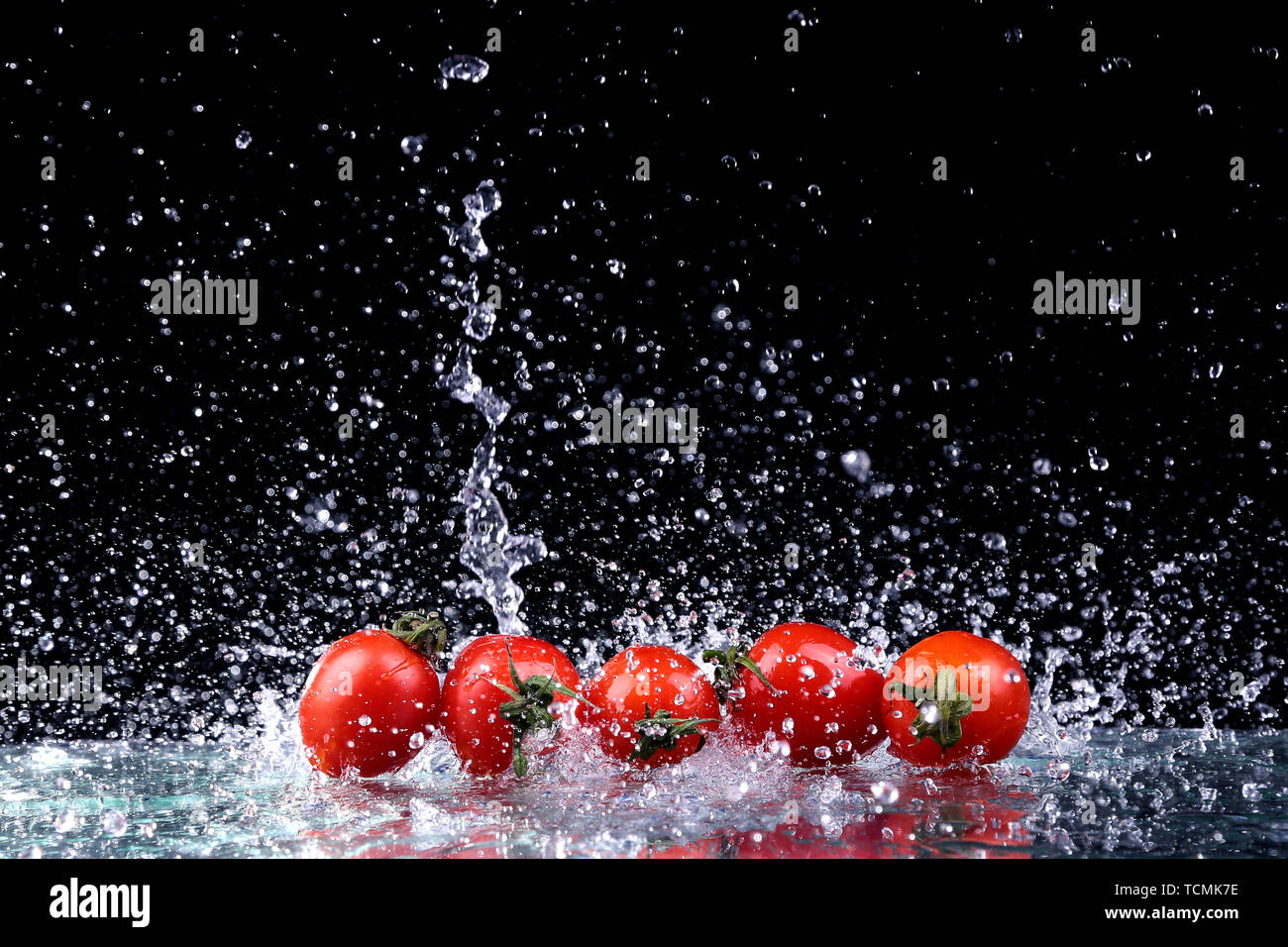 Studio shot with freeze motion of cherry tomatoes in water splash on ...