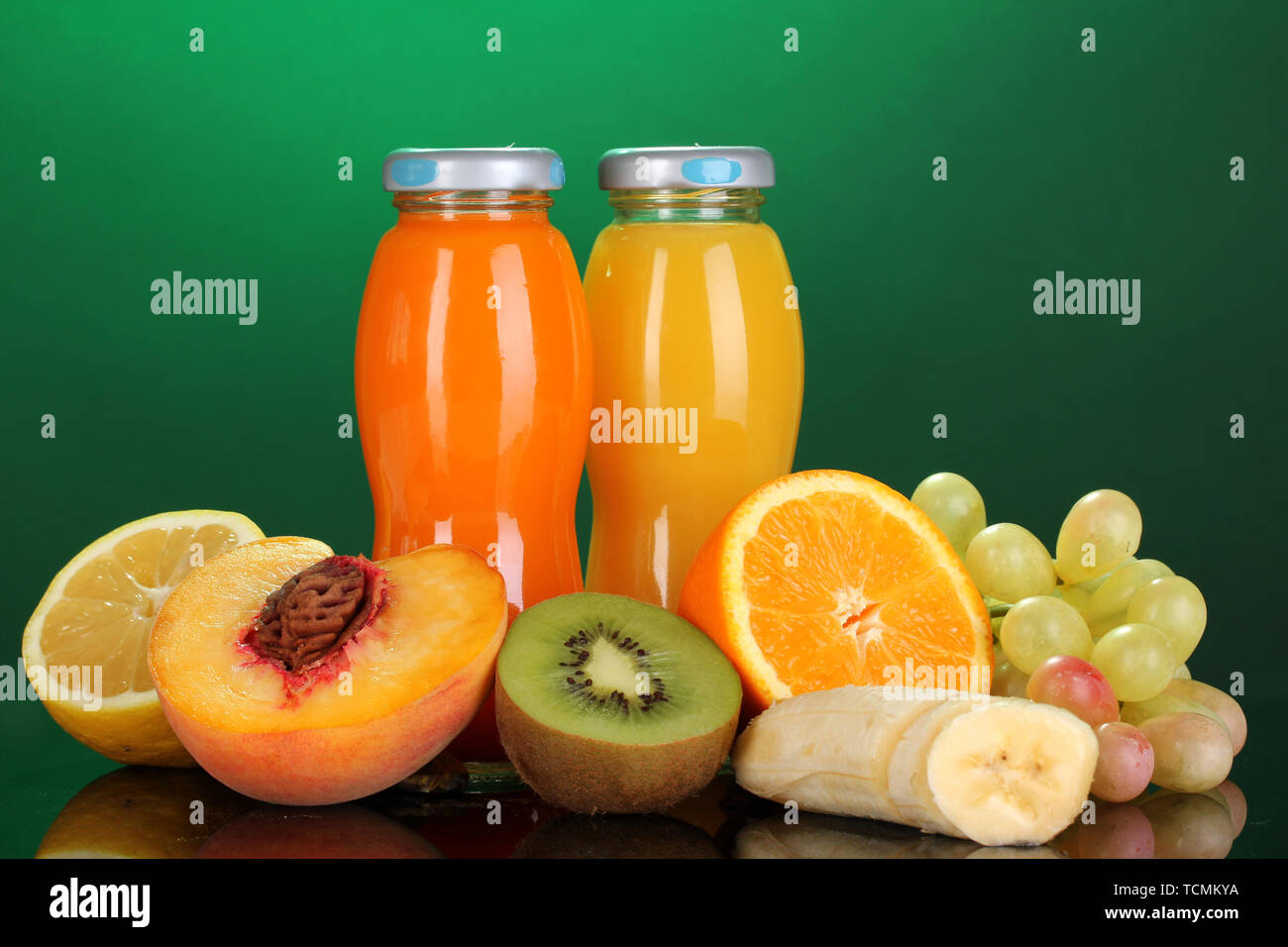 Delicious multifruit juice in a bottle and fruit next to it on green ...