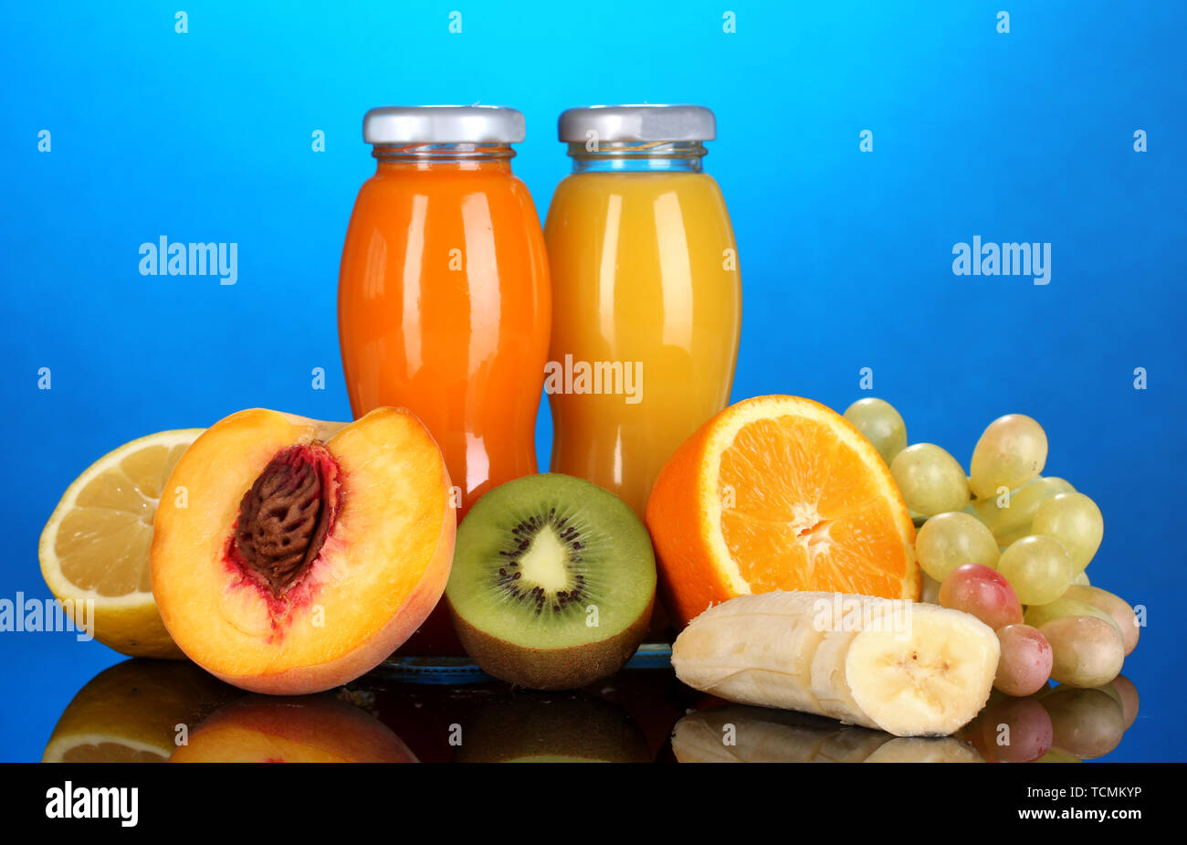 Delicious multifruit juice in a bottle and fruit next to it on blue ...