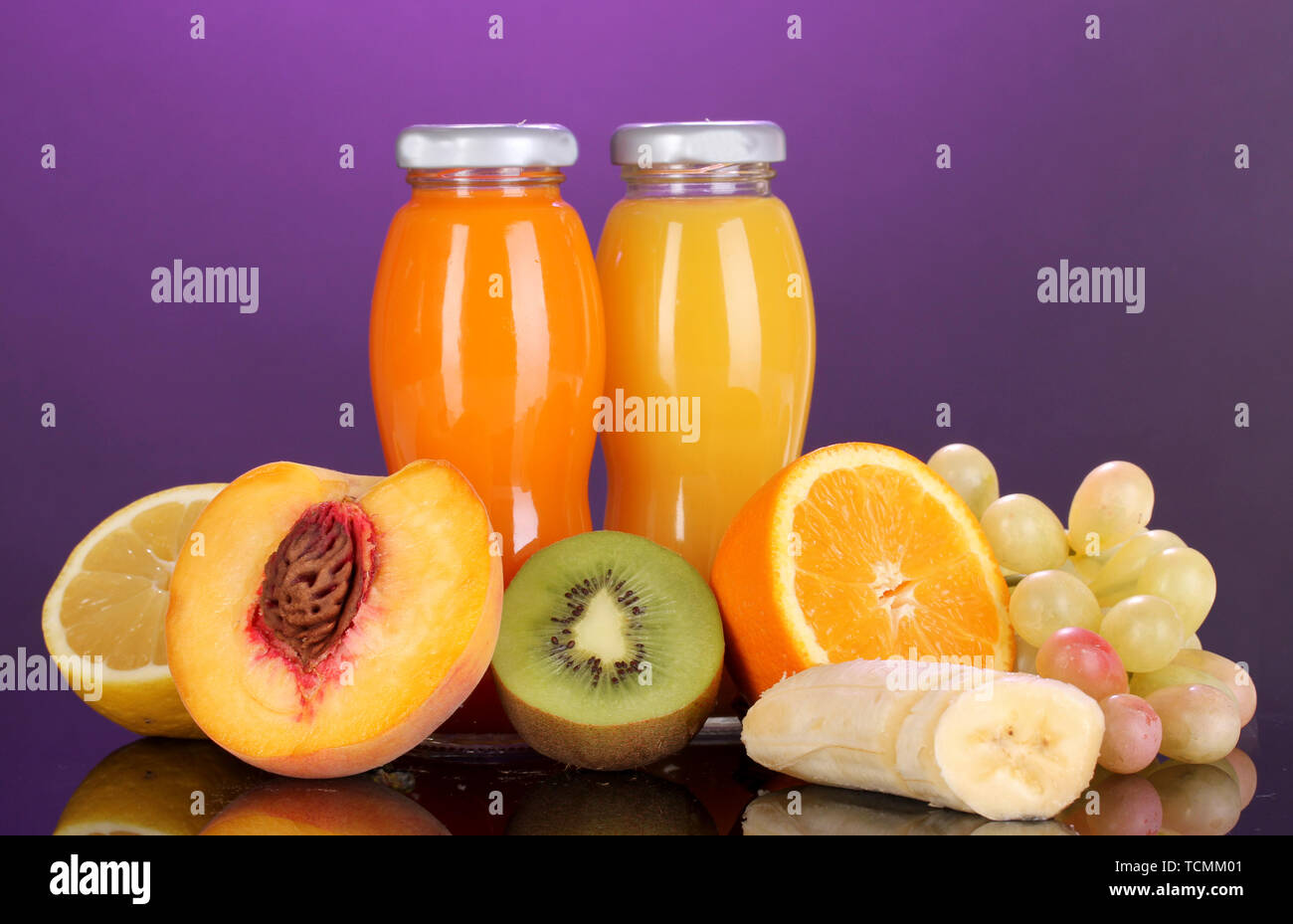 Delicious multifruit juice in a bottle and fruit next to it on purple ...