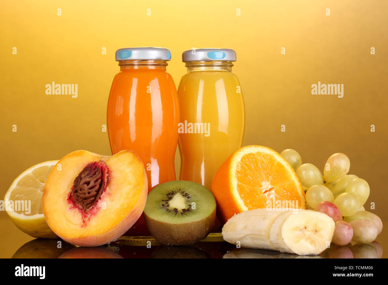 Delicious multifruit juice in a bottle and fruit next to it on yellow ...