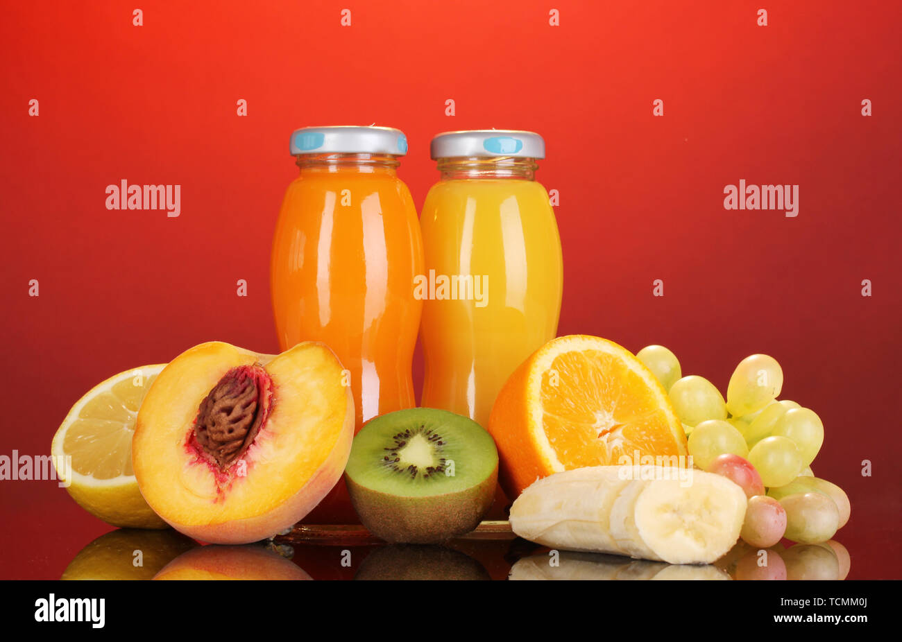 Delicious multifruit juice in a bottle and fruit next to it on red ...